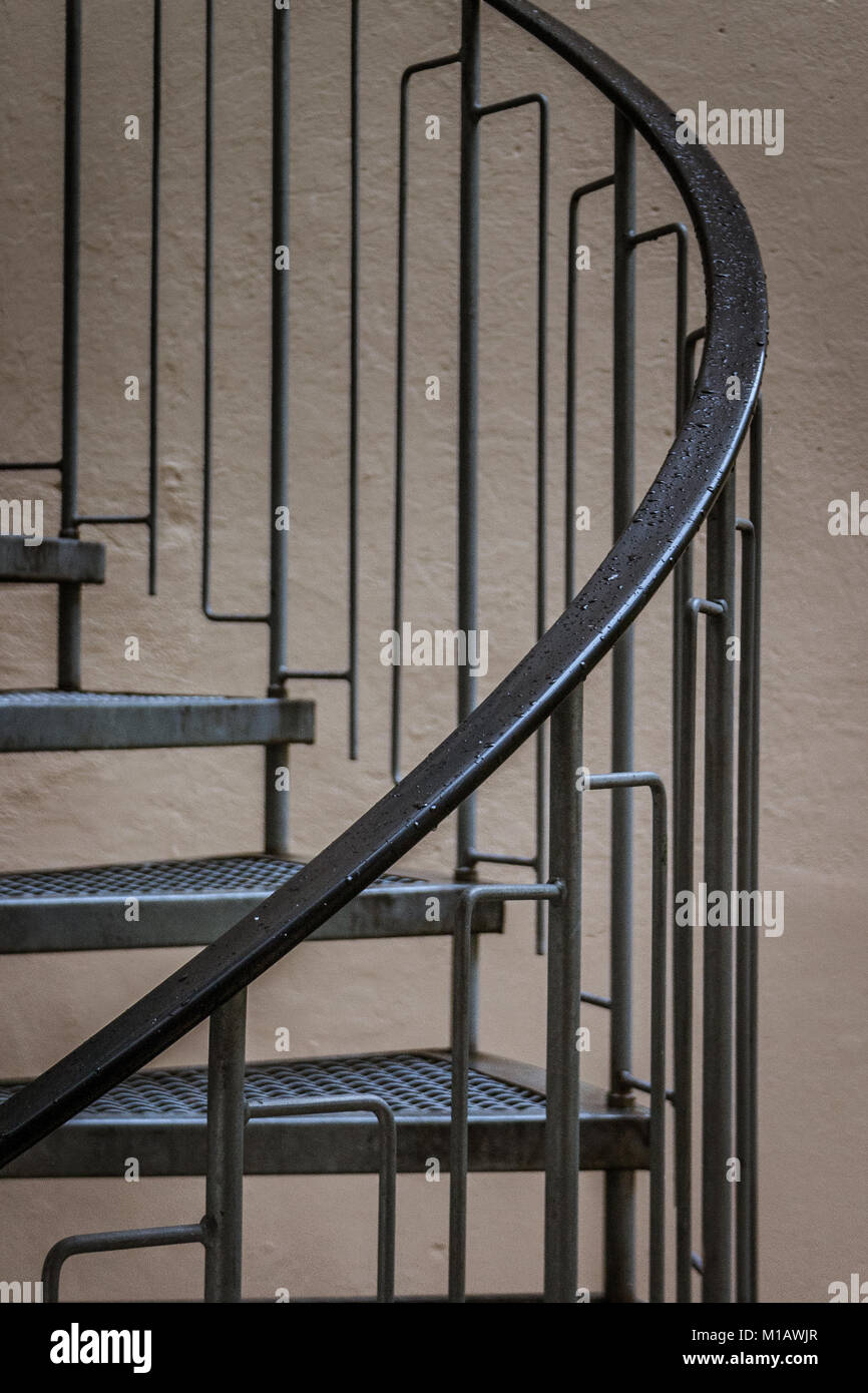Partial shot of steel fire escape stairs in front of beige wall ...