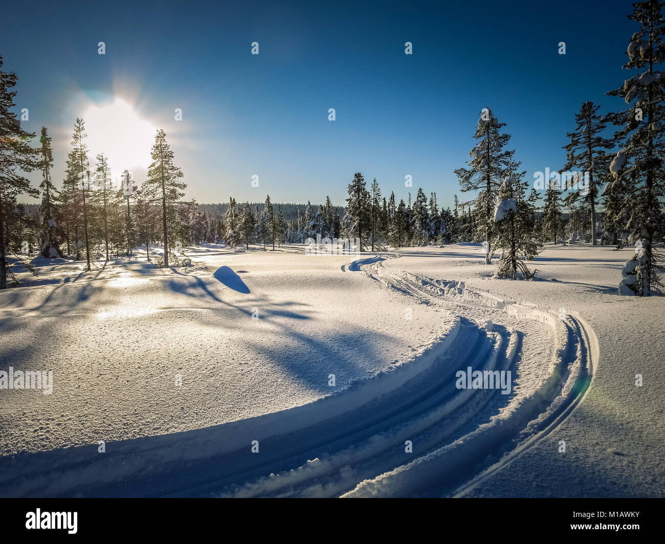 Single-track snow mobile tracks through winter landscape. Ski track ...