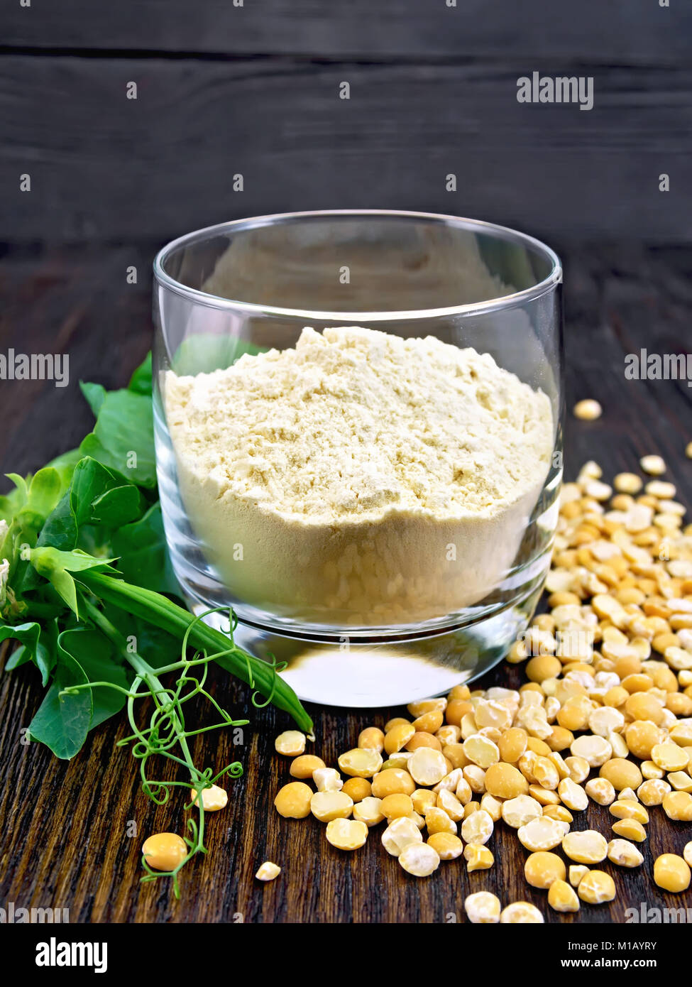 Flour pea in a glassful, fresh pods and split pease on a dark wooden ...