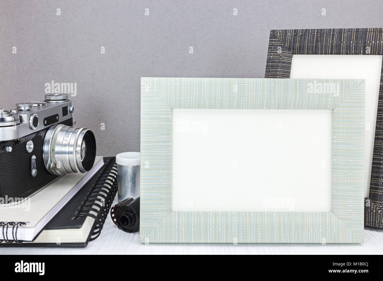 empty photo frames with old camera and notepads on table against grey ...