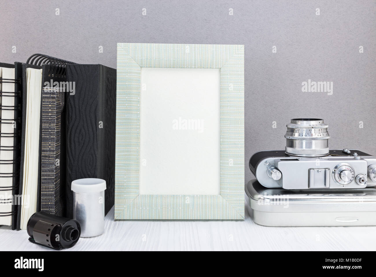 old camera, notebooks, photo frame, roll film on grey background ...