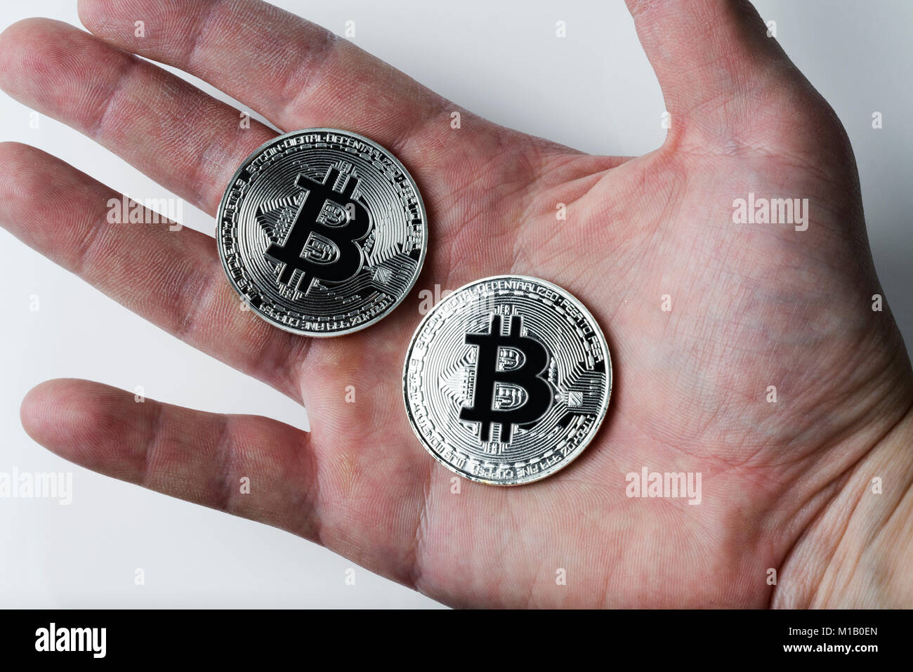 Two silver bitcoin in the hand on white background. Digital currency ...