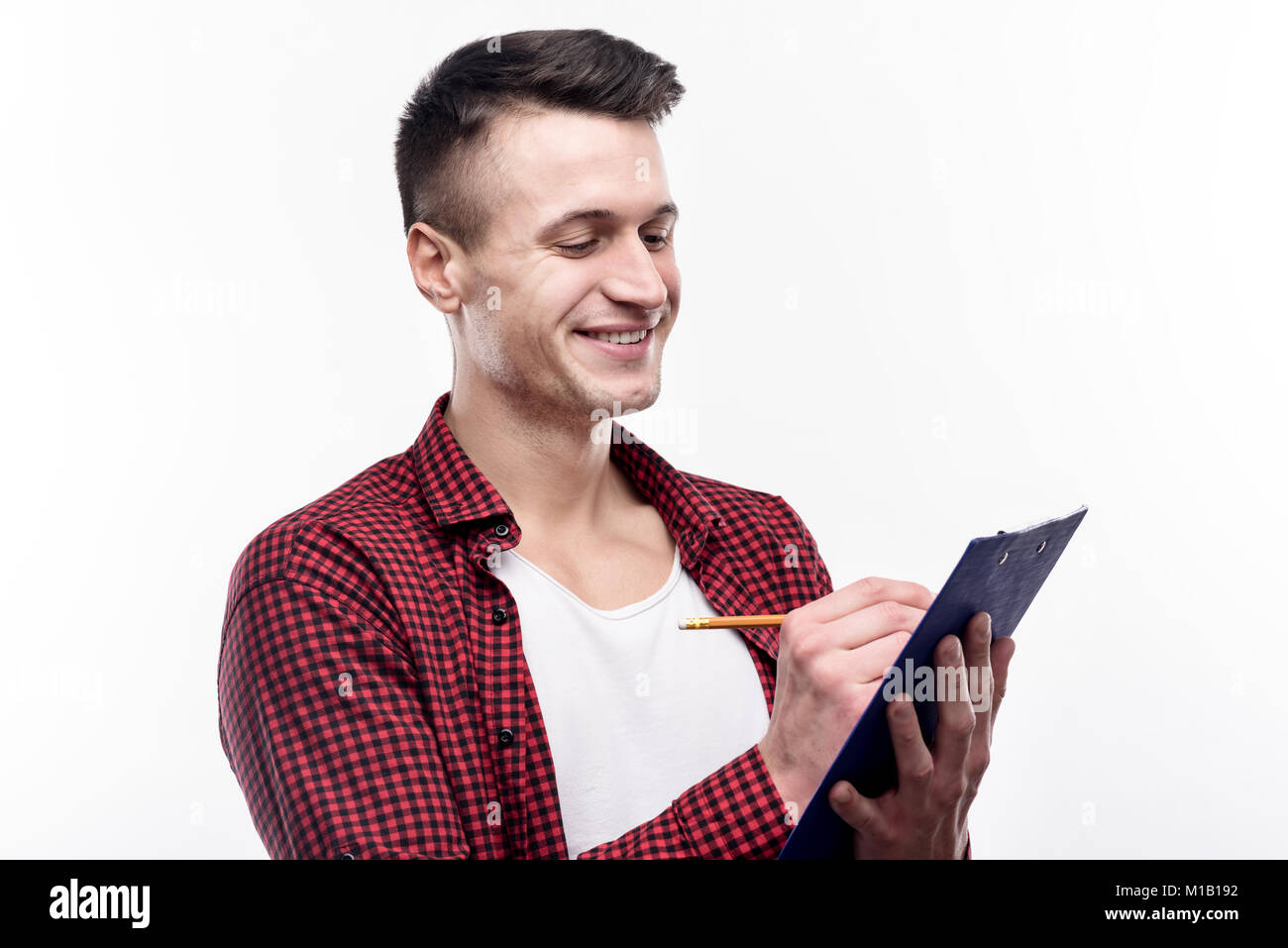 Charming young man making notes on sheet holder Stock Photo - Alamy