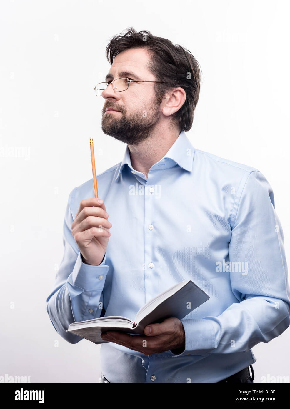 Pleasant professor thinking what to write in notebook Stock Photo - Alamy