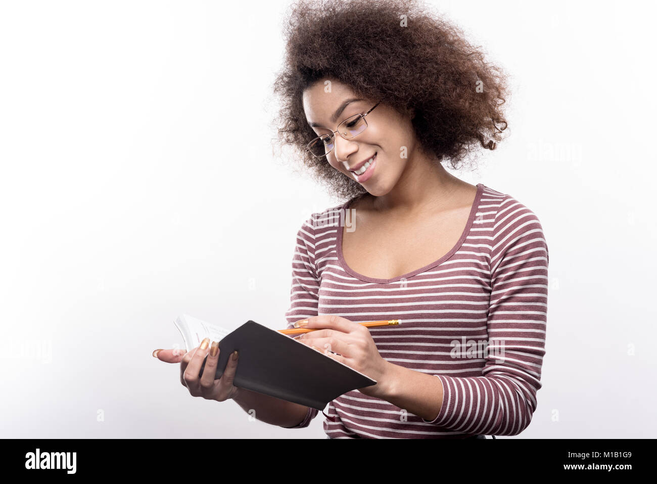 Curly-haired young woman taking notes Stock Photo - Alamy