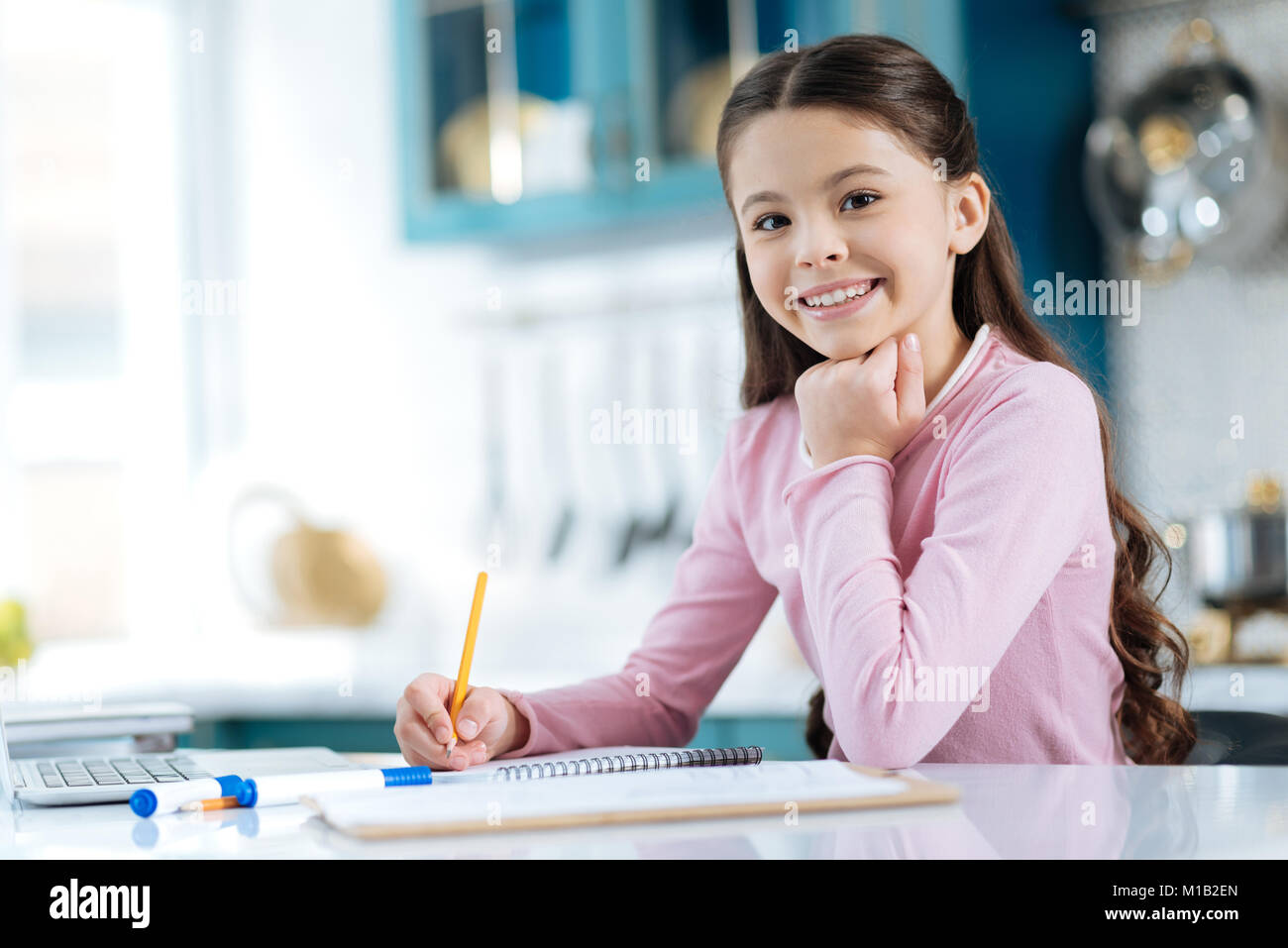 Happy girl writing and holding her head with her hand Stock Photo - Alamy
