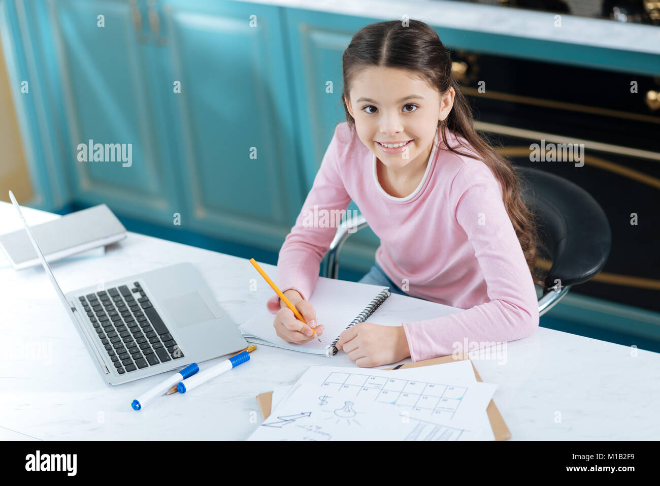 Inspired girl doing her homework and smiling Stock Photo - Alamy