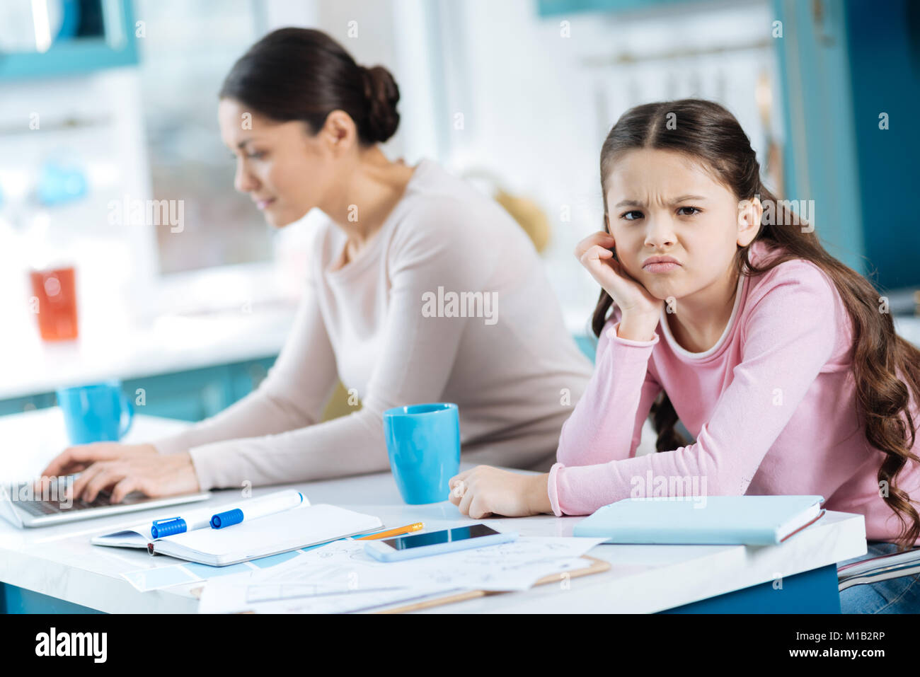 Unhappy bored girl and her mom working Stock Photo - Alamy