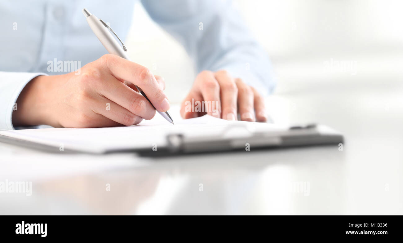 Woman's hands writing on sheet of paper in a clipboard with pen ...