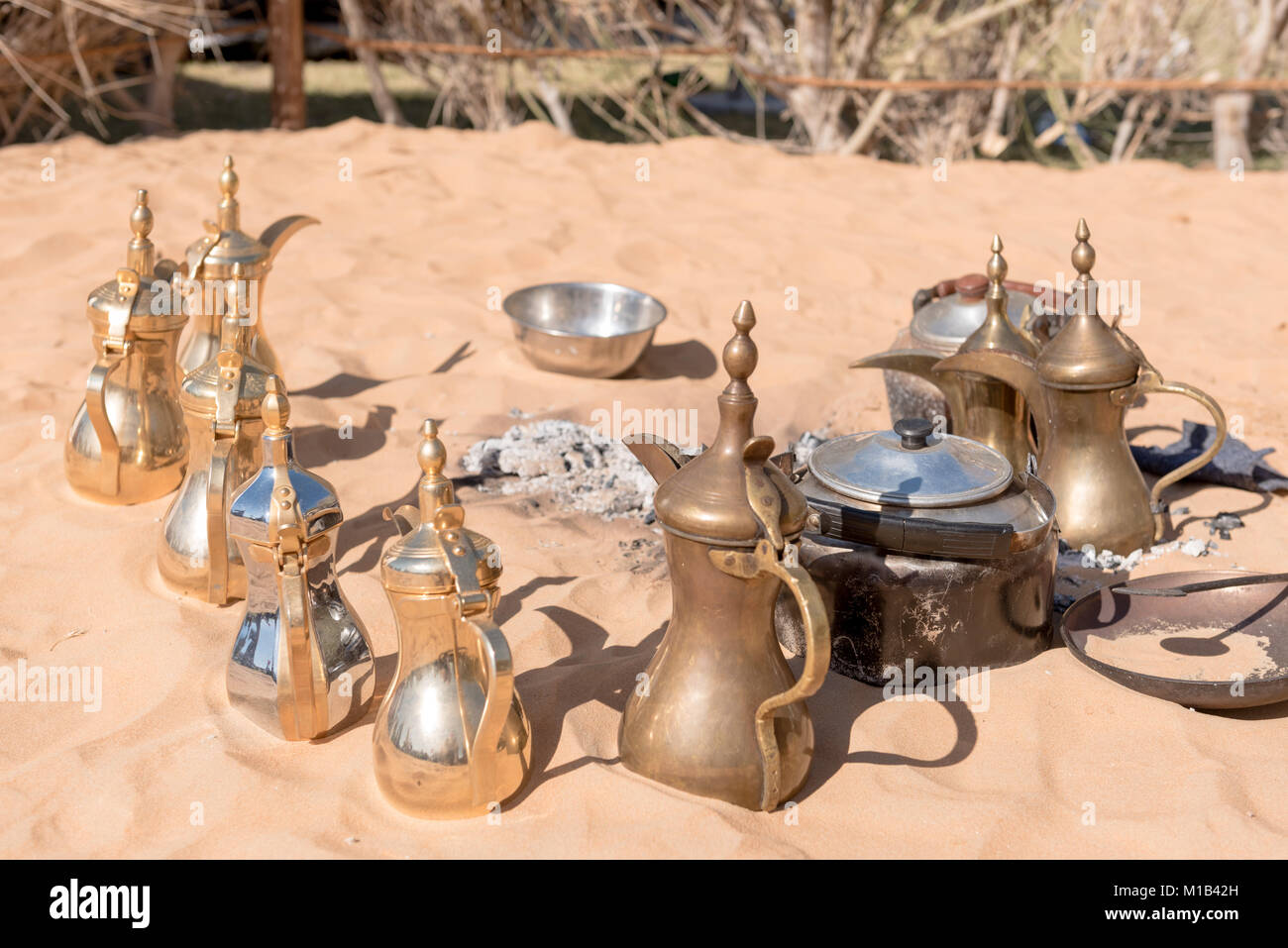 Brass coffee pots around a fire pit in the desert. Setting for a ...