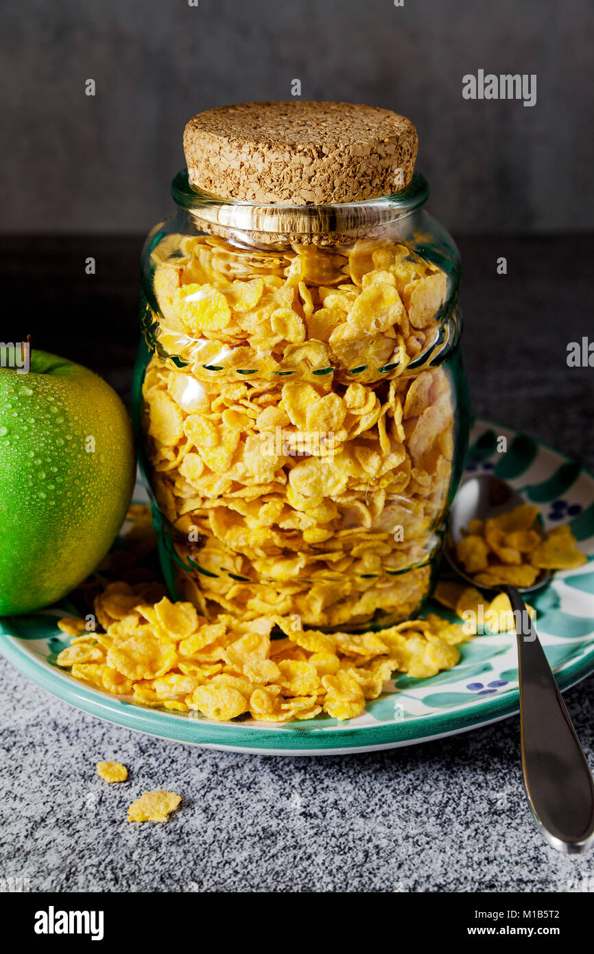 Cornflake cereals in a glass jar for storage with milk and a green ...