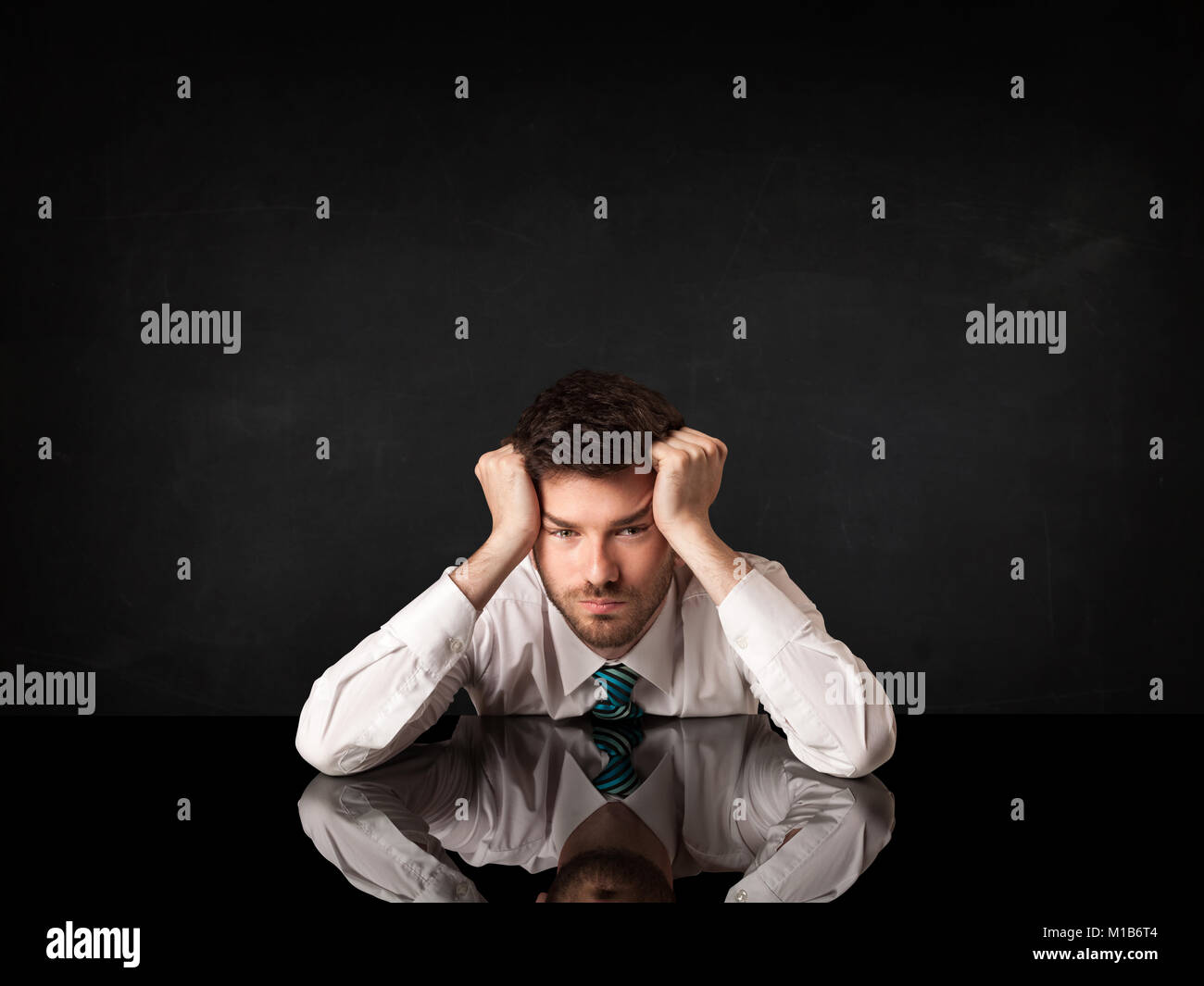 Depressed businessman sitting at a desk Stock Photo - Alamy