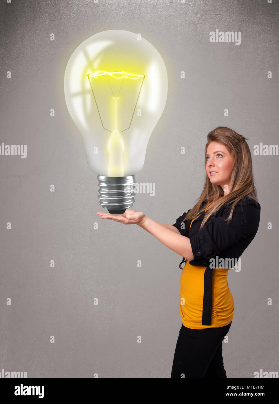 Beautiful young lady holding realistic 3d light bulb Stock Photo - Alamy