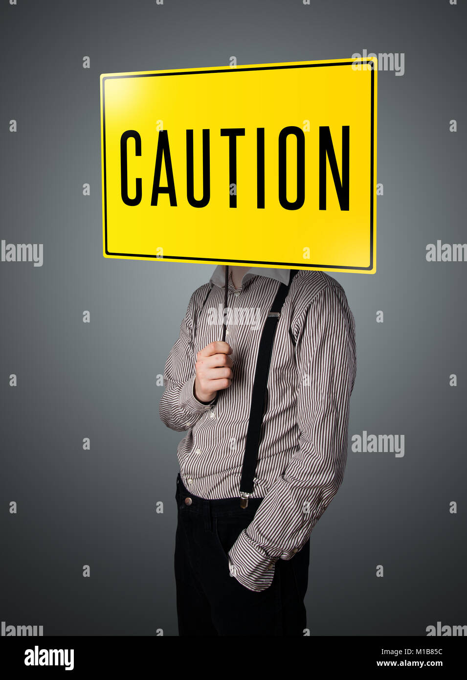 Businessman standing and holding a yellow caution sign in front of his ...
