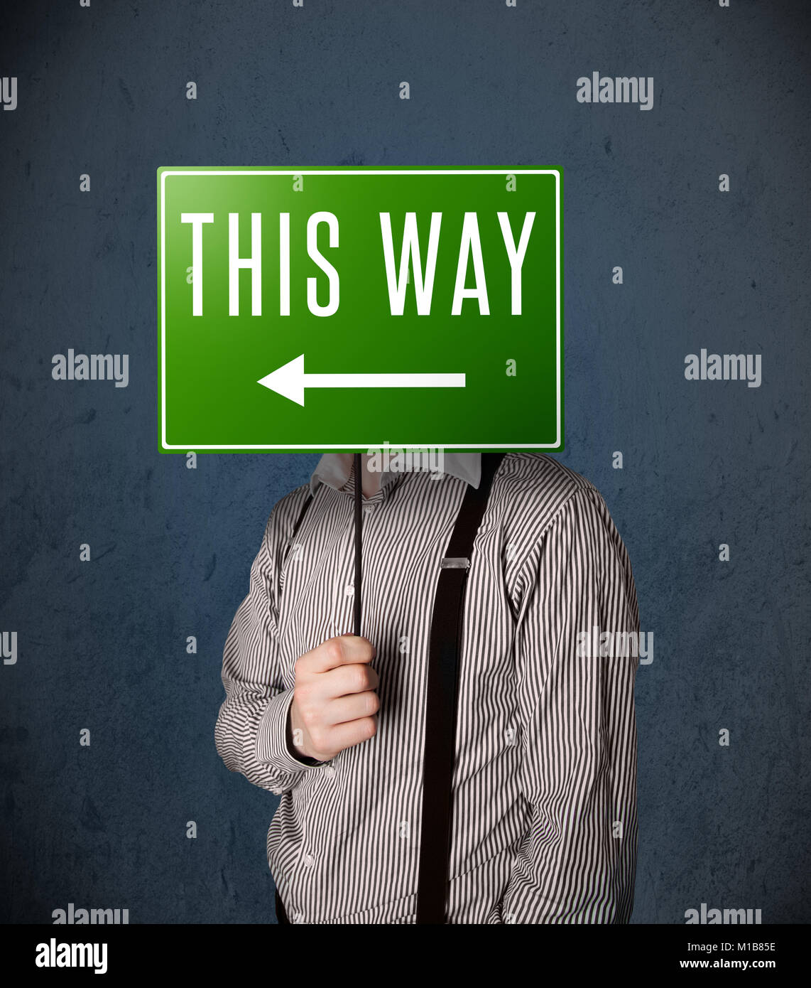 Businessman standing and holding a green direction sign in front of his ...