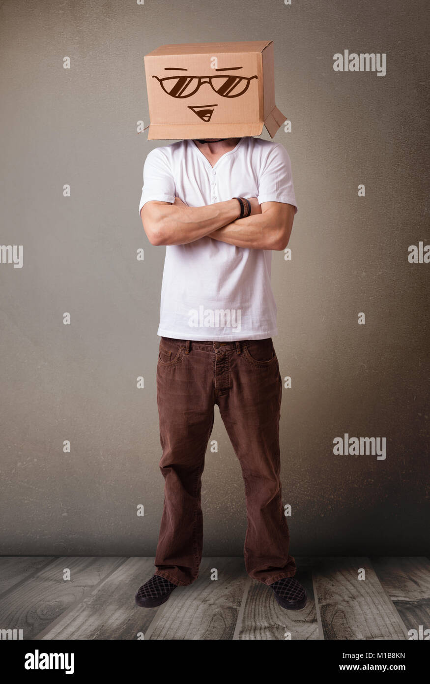 Young man standing and gesturing with a cardboard box on his head with ...