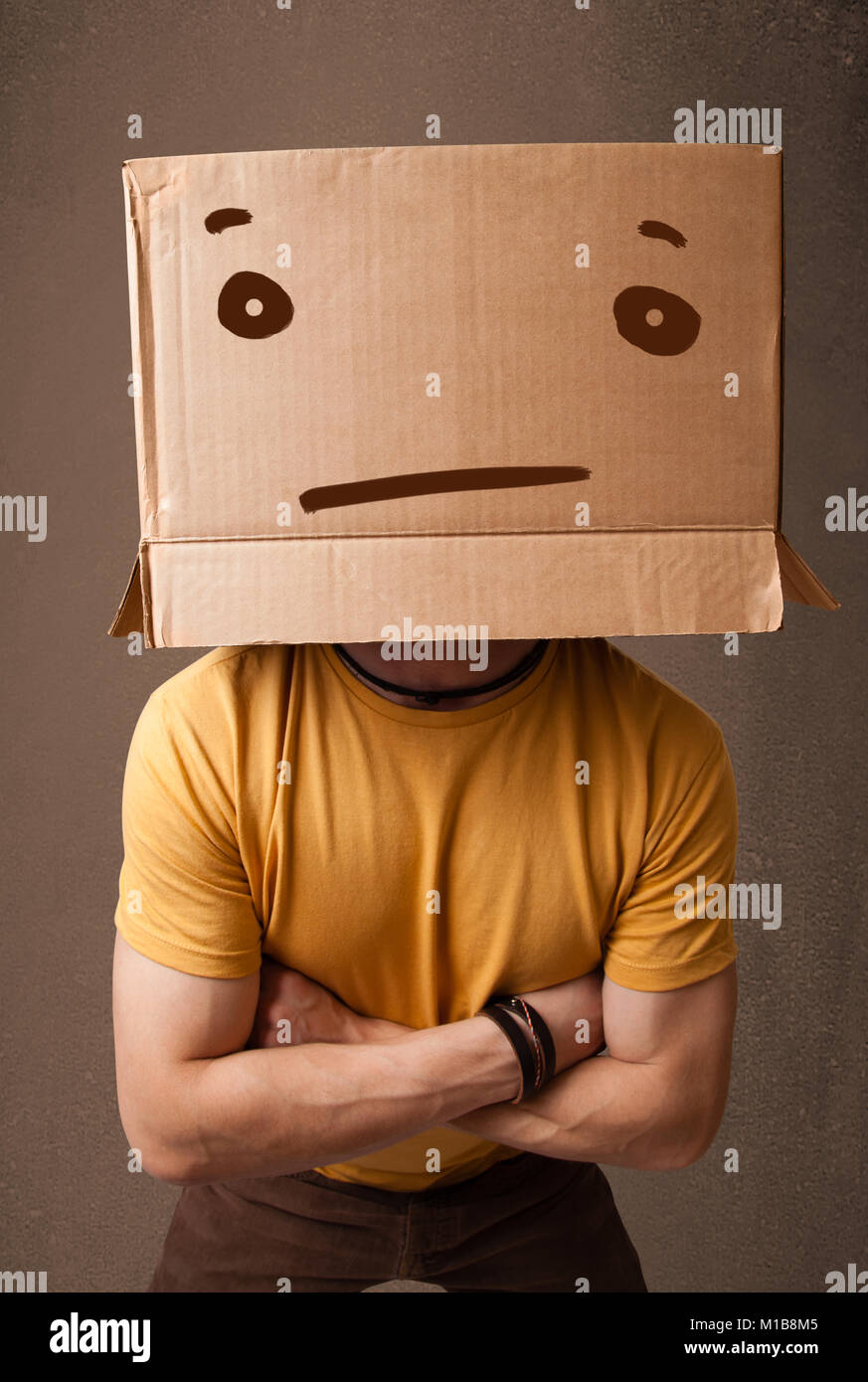 Young man standing and gesturing with a cardboard box on his head with ...
