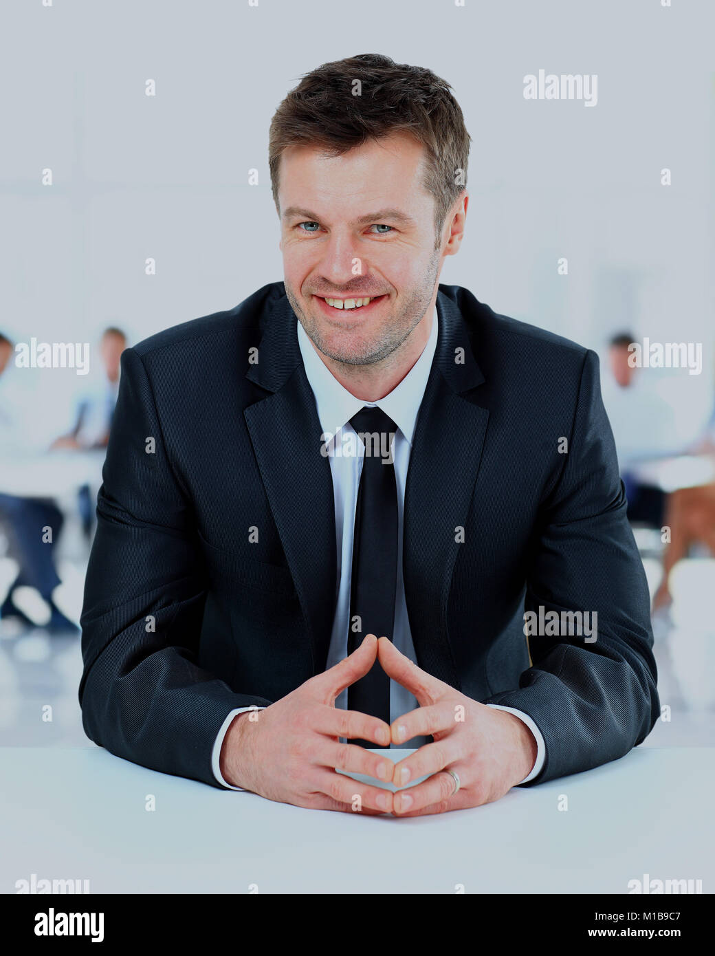 Portrait of smiling businessman sitting at a table of the background of ...