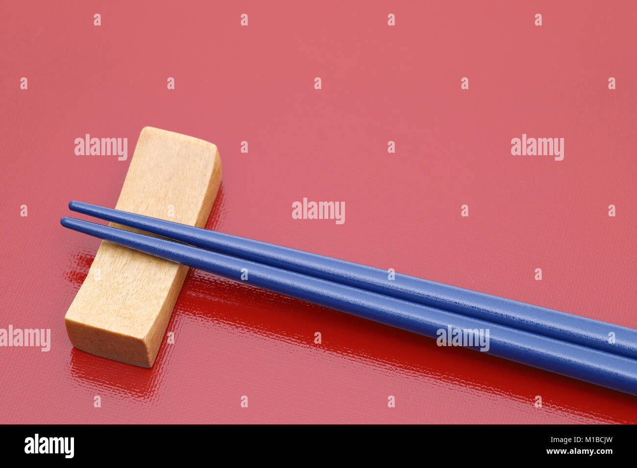 Chopsticks and chopsticks-rest on a red tray background Stock Photo - Alamy
