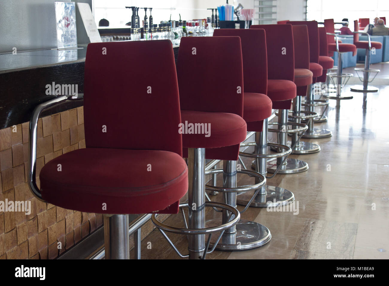 Bar with a long counter and a high bar red chairs Stock Photo - Alamy