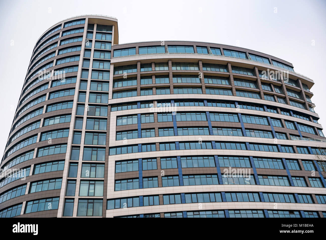 Bottom view of tall modern building with offices against grey sky Stock ...
