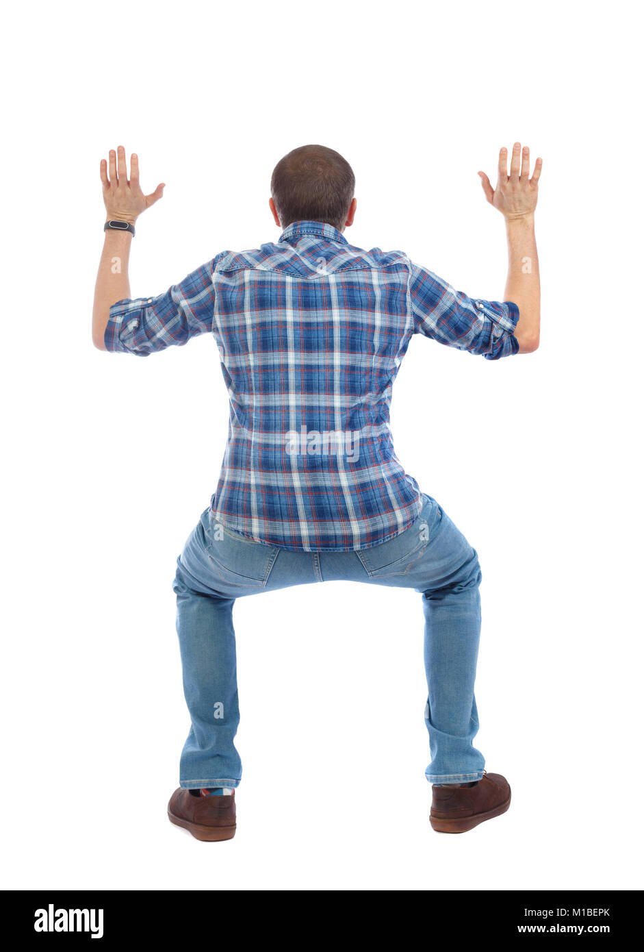 back view. man protects hands from what is falling from above. Man ...