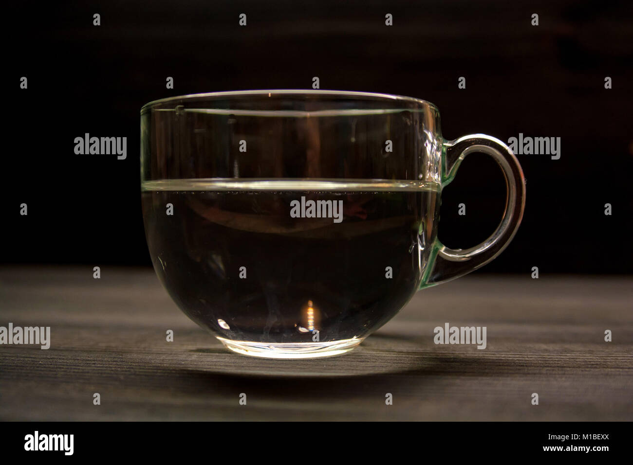 Close up transparent tea mug filled with water on black background ...