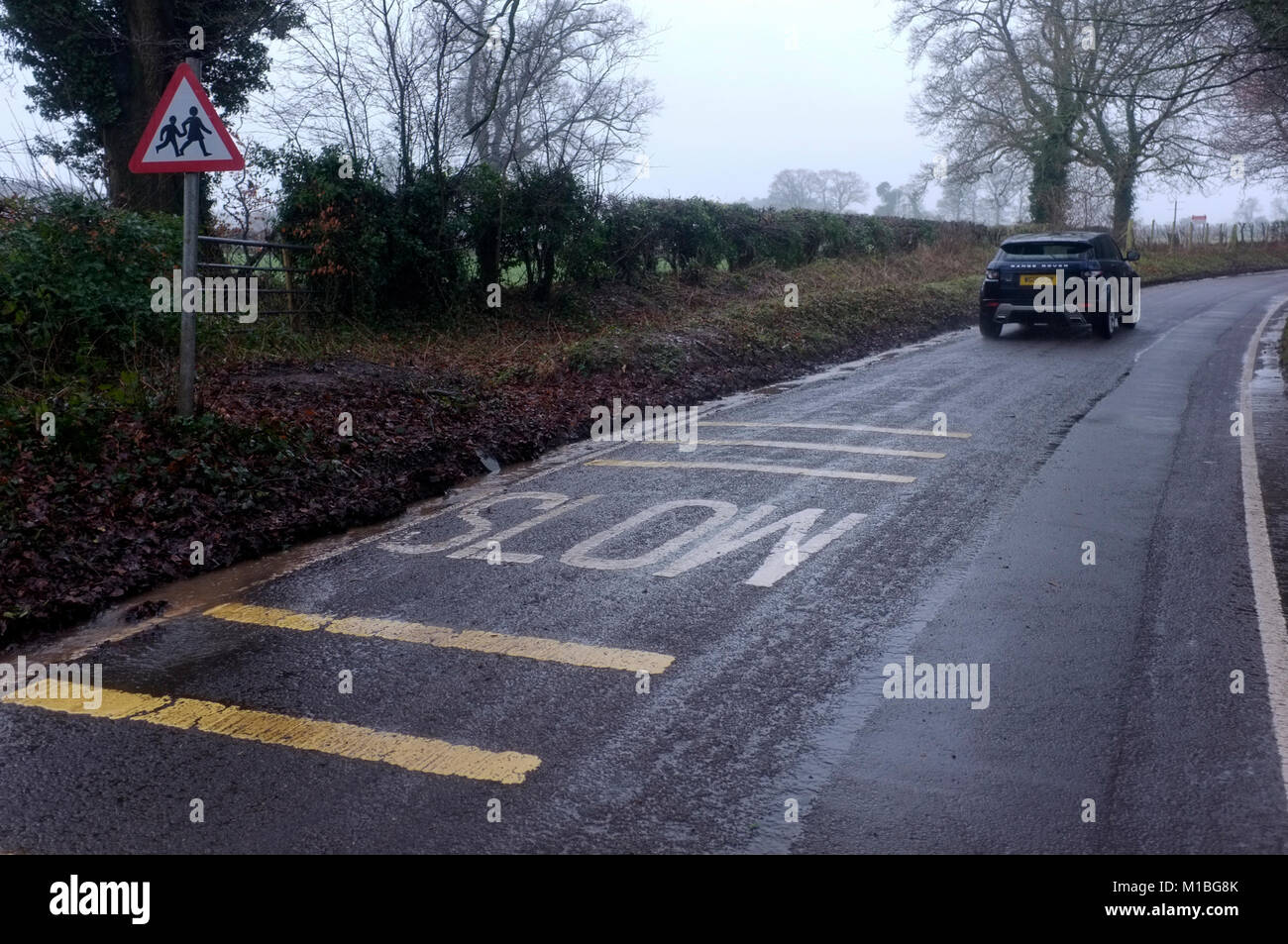 Traffic warning sign on a wet road in winter Stock Photo - Alamy