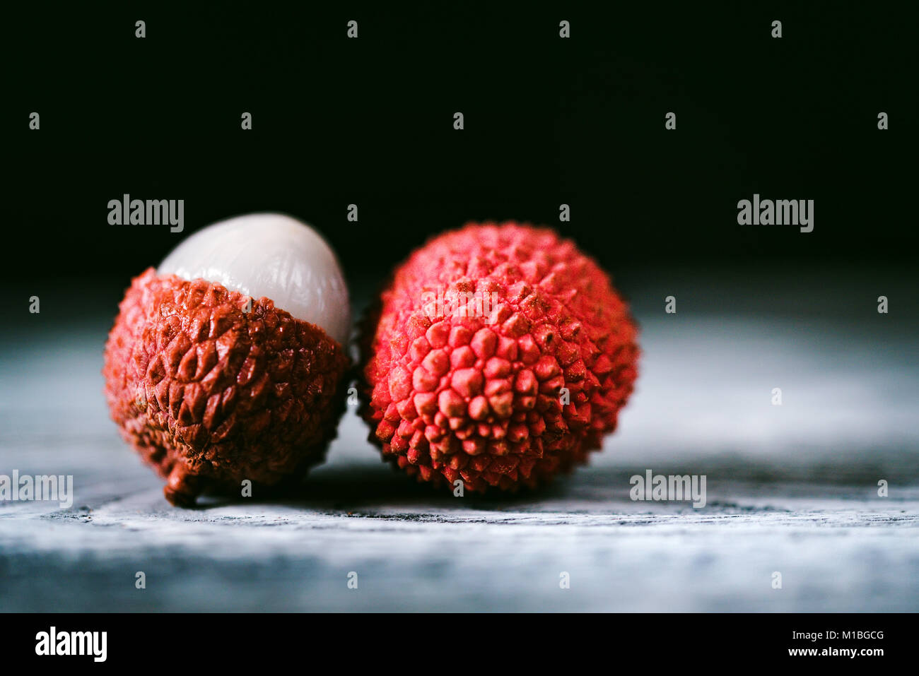 Two lychee fruits dark background Stock Photo - Alamy