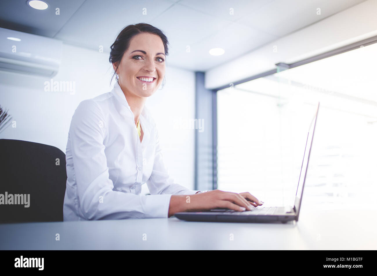 Beautiful brunette female business woman working on her laptop in her ...