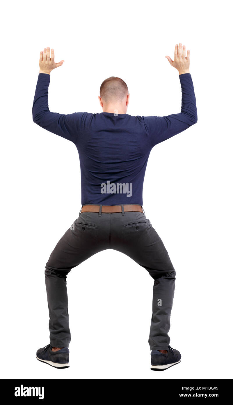 back view. man protects hands from what is falling from above. Man ...