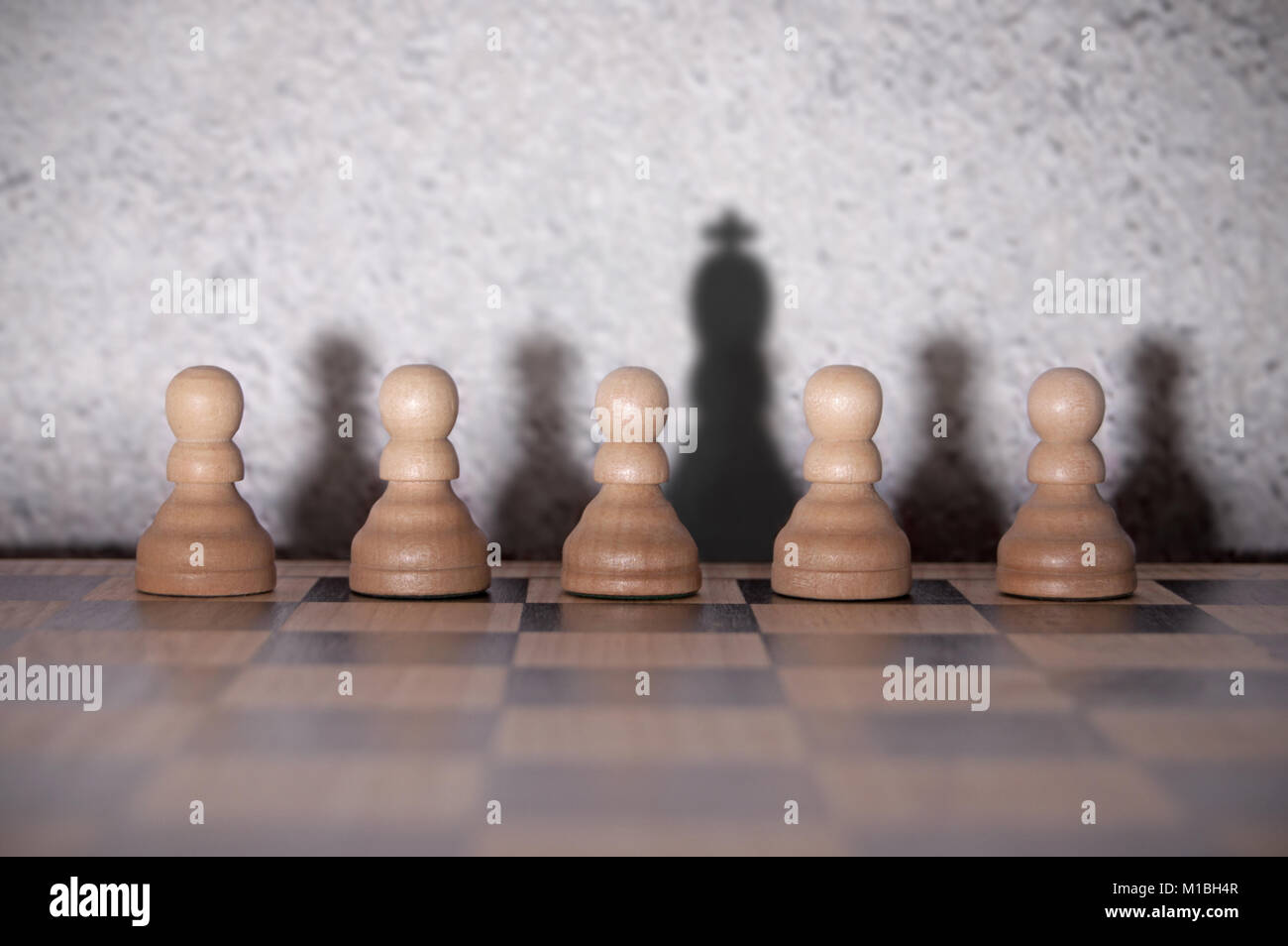 Chess king shadow standing out in a row of pawns Stock Photo - Alamy
