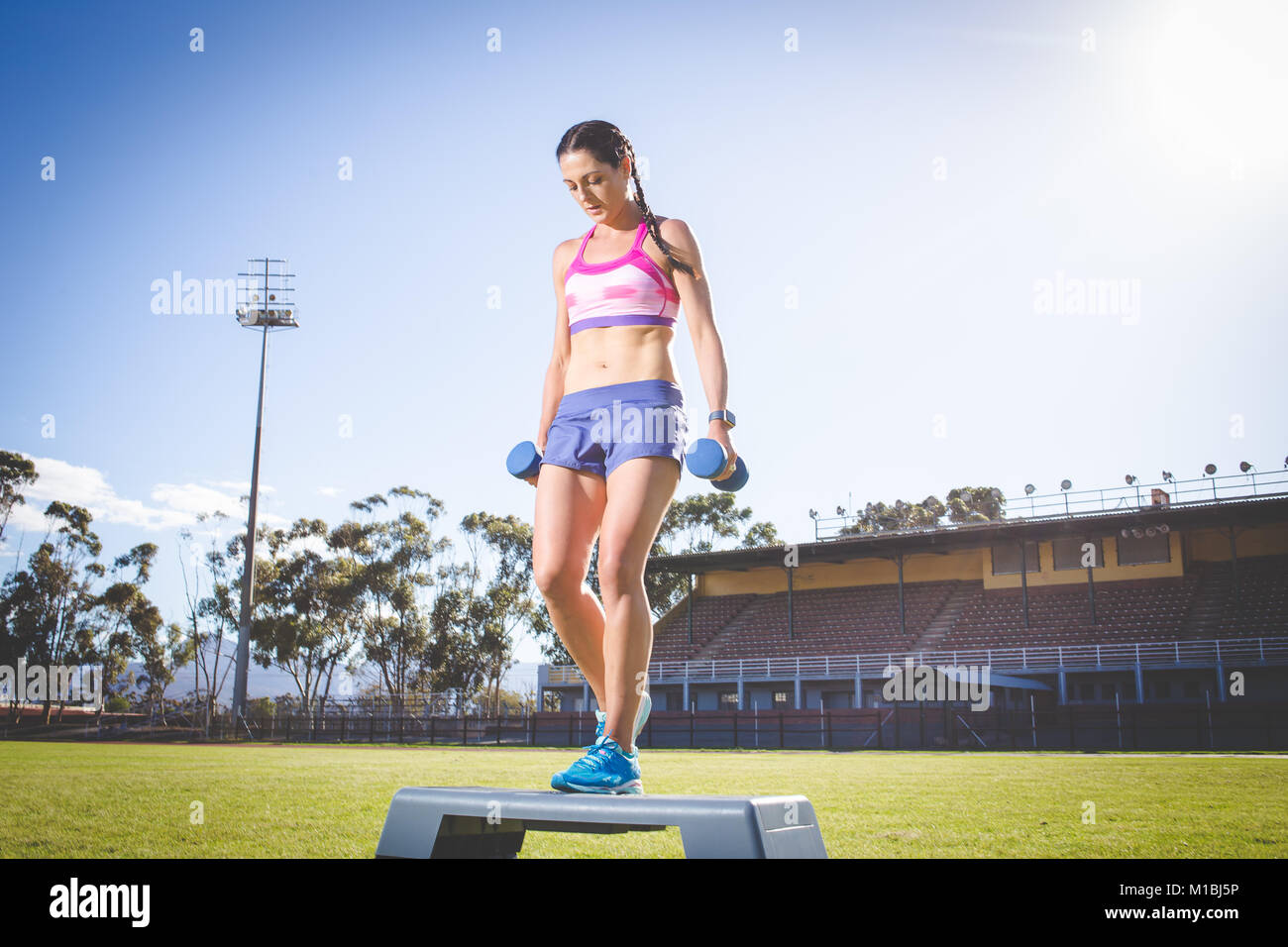 Female fitness model doing exercises outside at a sport stadium on a ...