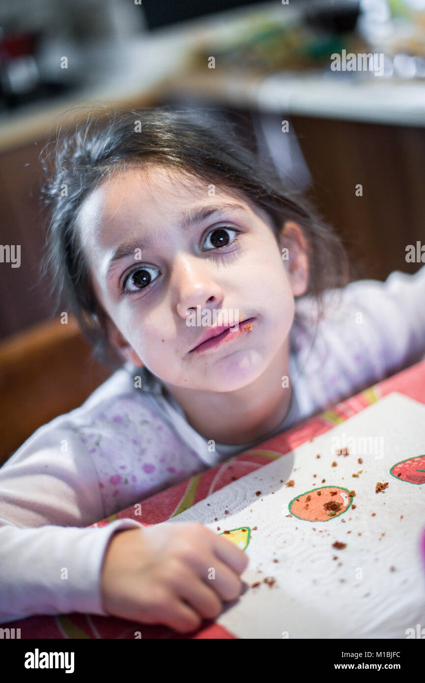 portrait of serious little girl with cake crumbs dirty mouth looking ...