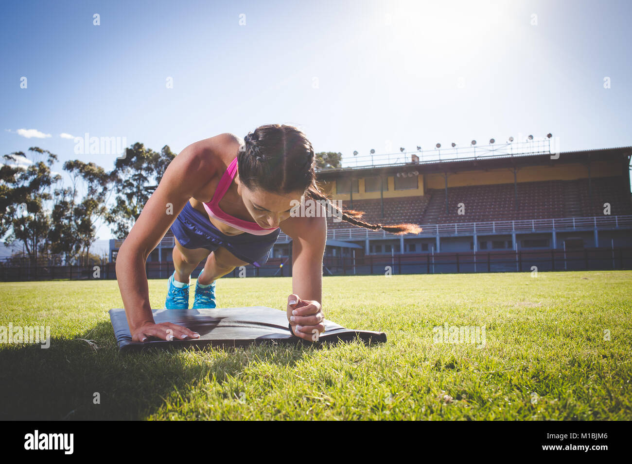 Female fitness model doing exercises outside at a sport stadium on a ...
