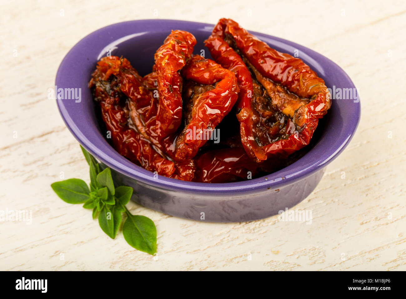 Dried tomato in olive oil with basil leaves Stock Photo - Alamy