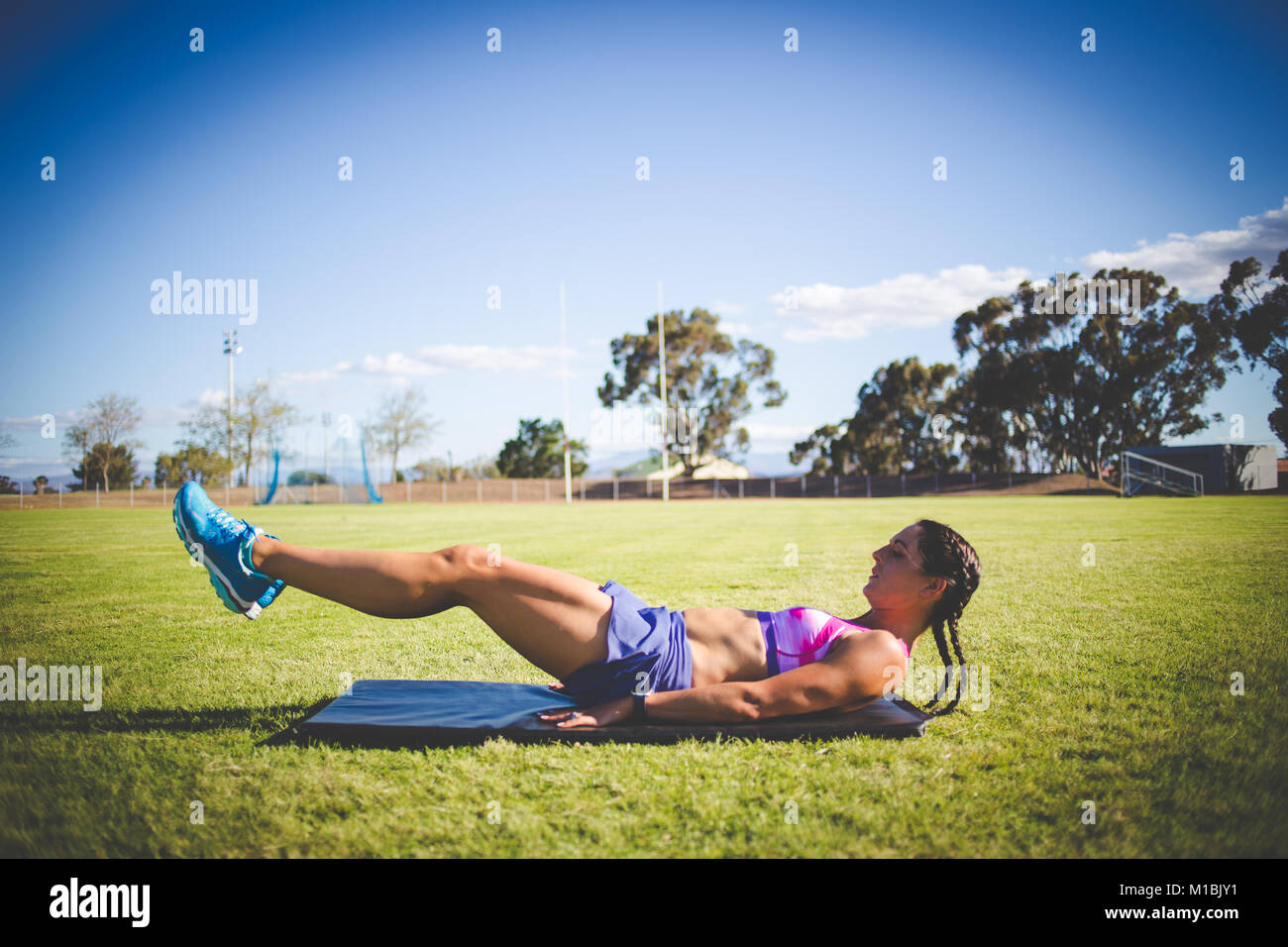 Female fitness model doing exercises outside at a sport stadium on a ...