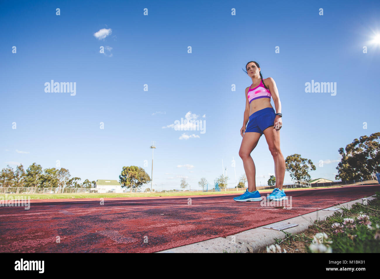 Female fitness model and track athlete sprinting on an athletics track ...