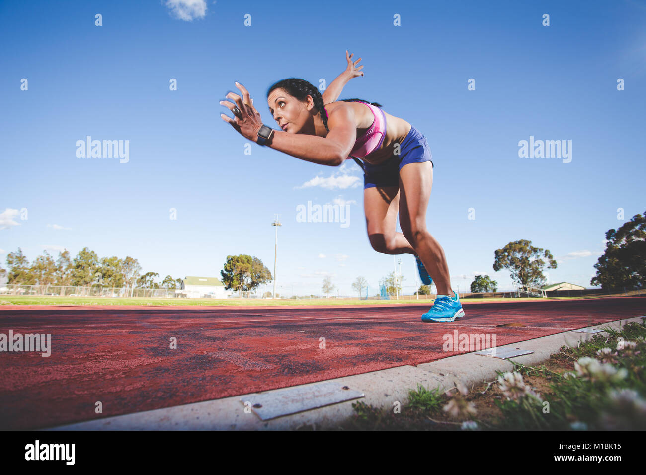 Female fitness model and track athlete sprinting on an athletics track ...