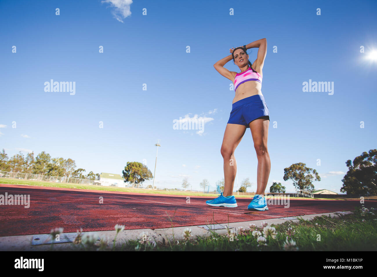 Female fitness model and track athlete sprinting on an athletics track ...