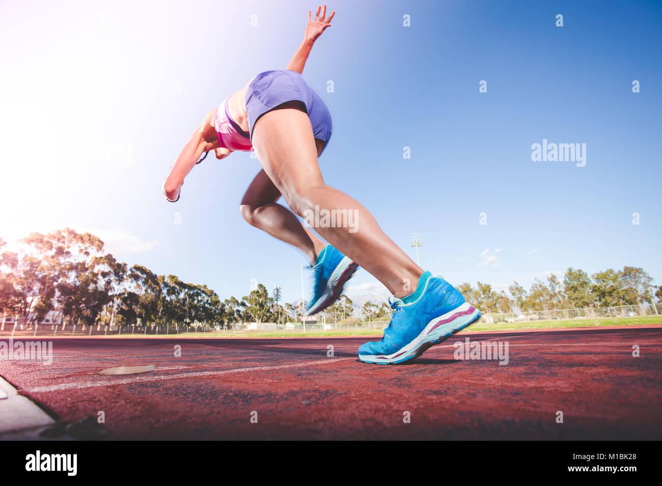 Female fitness model and track athlete sprinting on an athletics track ...