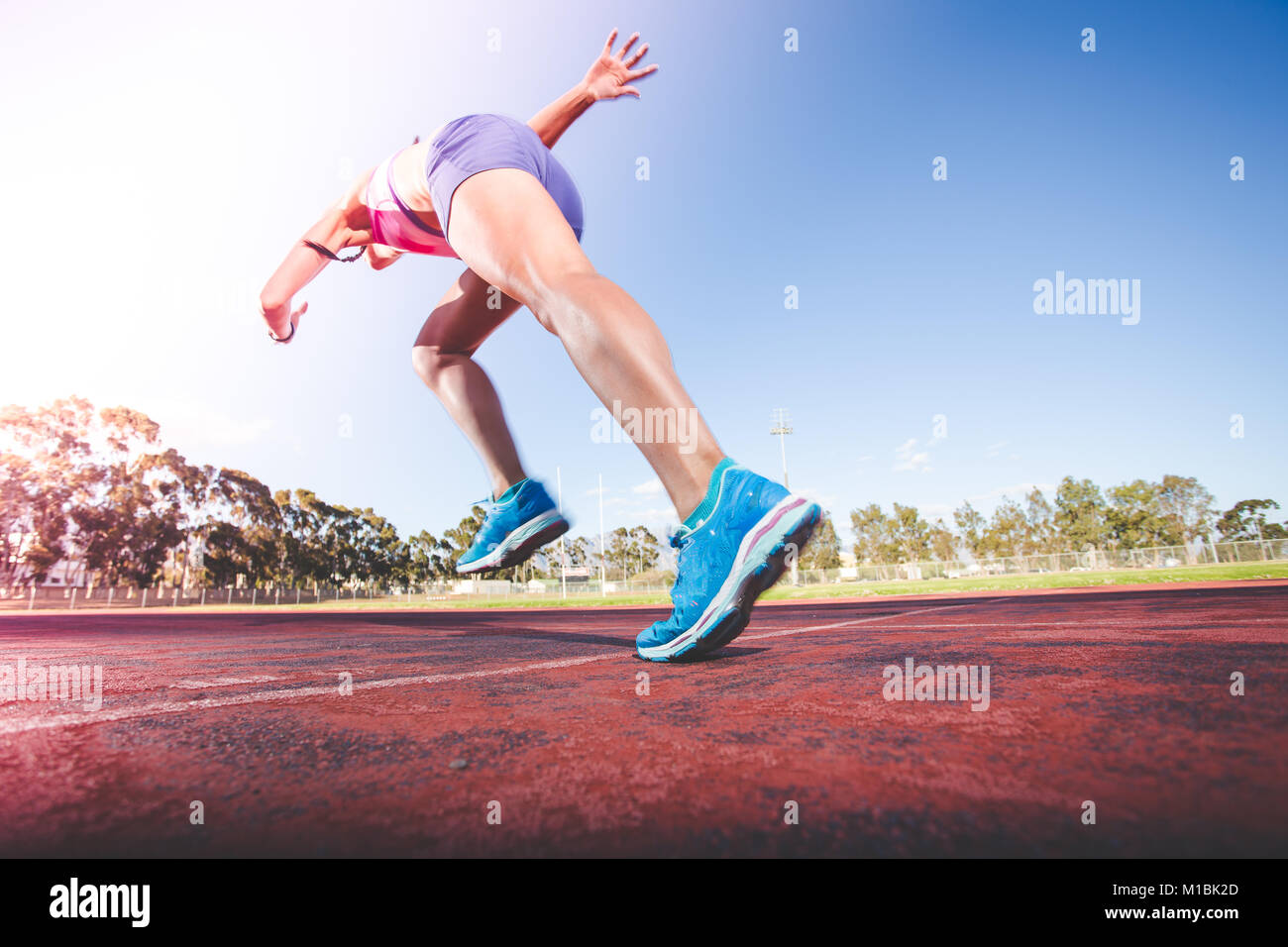 Female fitness model and track athlete sprinting on an athletics track ...