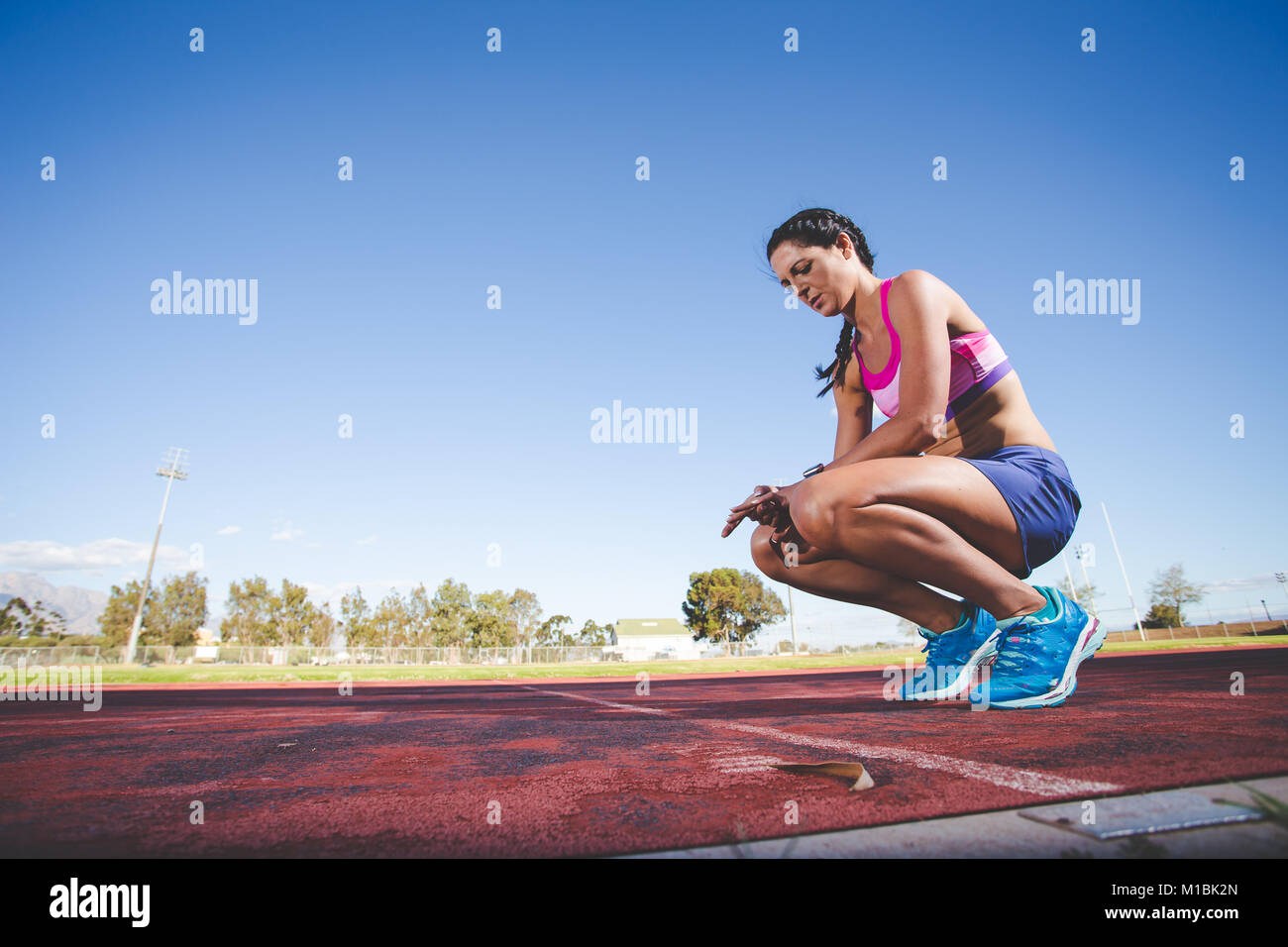 Female fitness model and track athlete sprinting on an athletics track ...