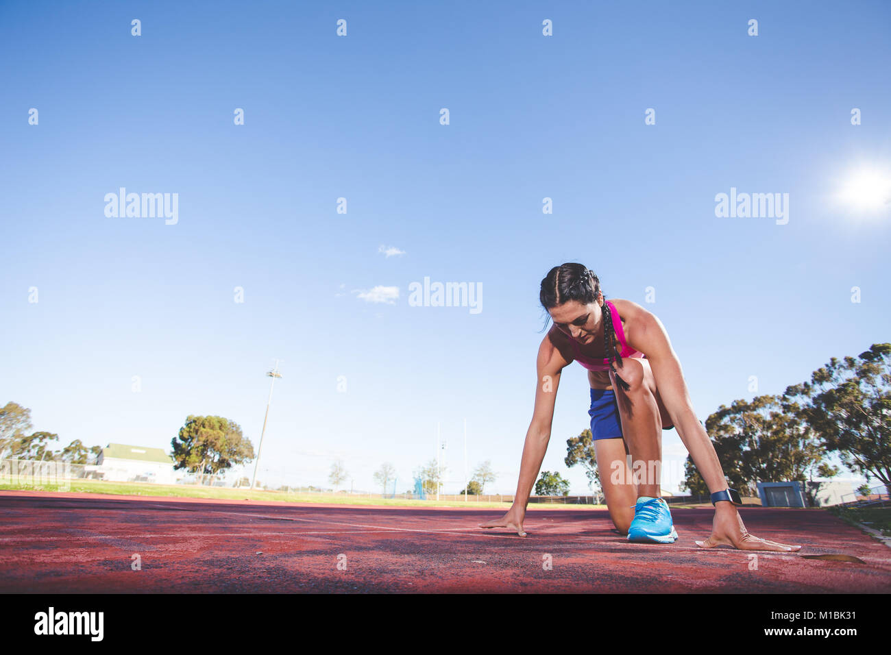 Female fitness model and track athlete sprinting on an athletics track ...