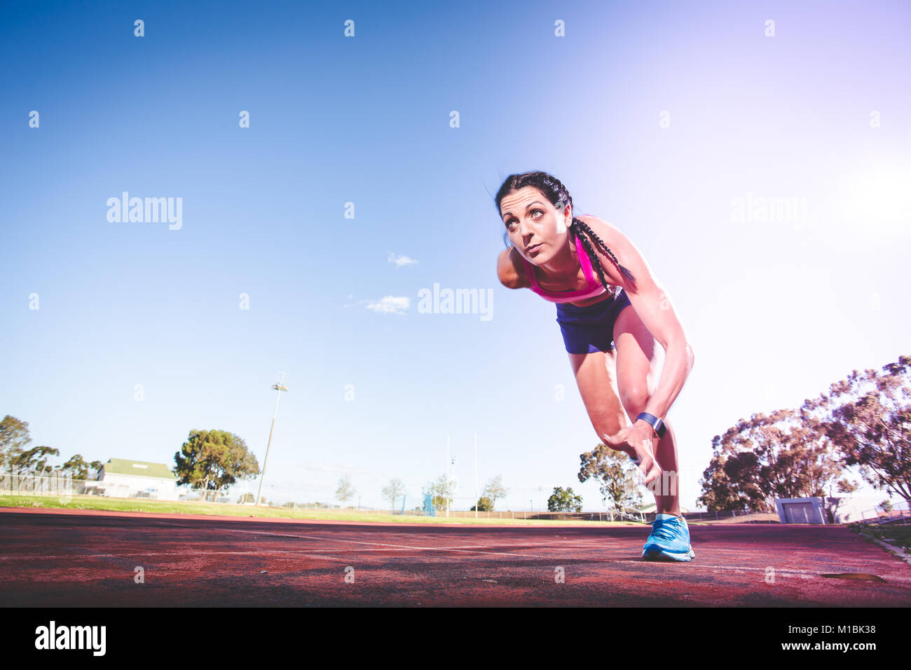 Female fitness model and track athlete sprinting on an athletics track ...