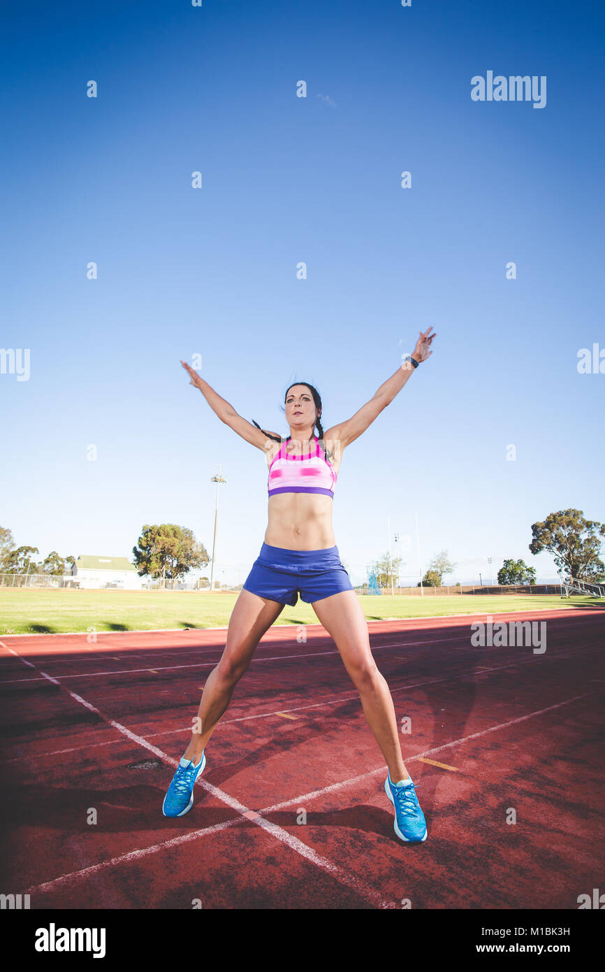 Female fitness model and track athlete sprinting on an athletics track ...