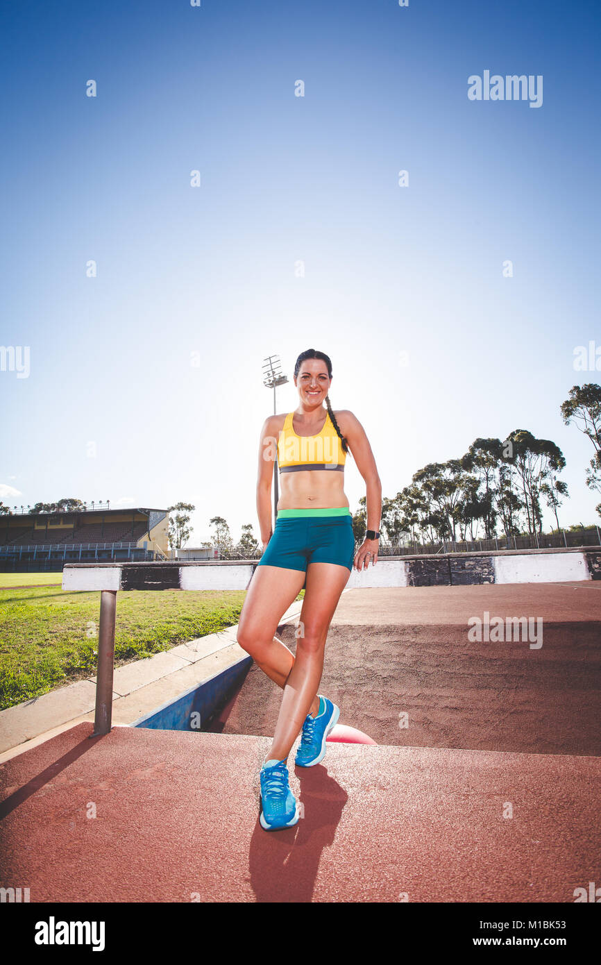 Female fitness model and track athlete sprinting on an athletics track ...