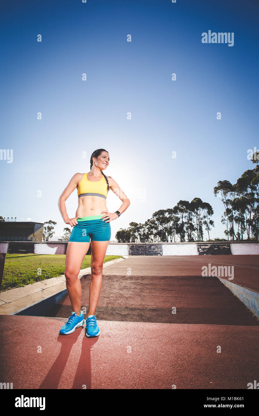 Female fitness model and track athlete sprinting on an athletics track ...