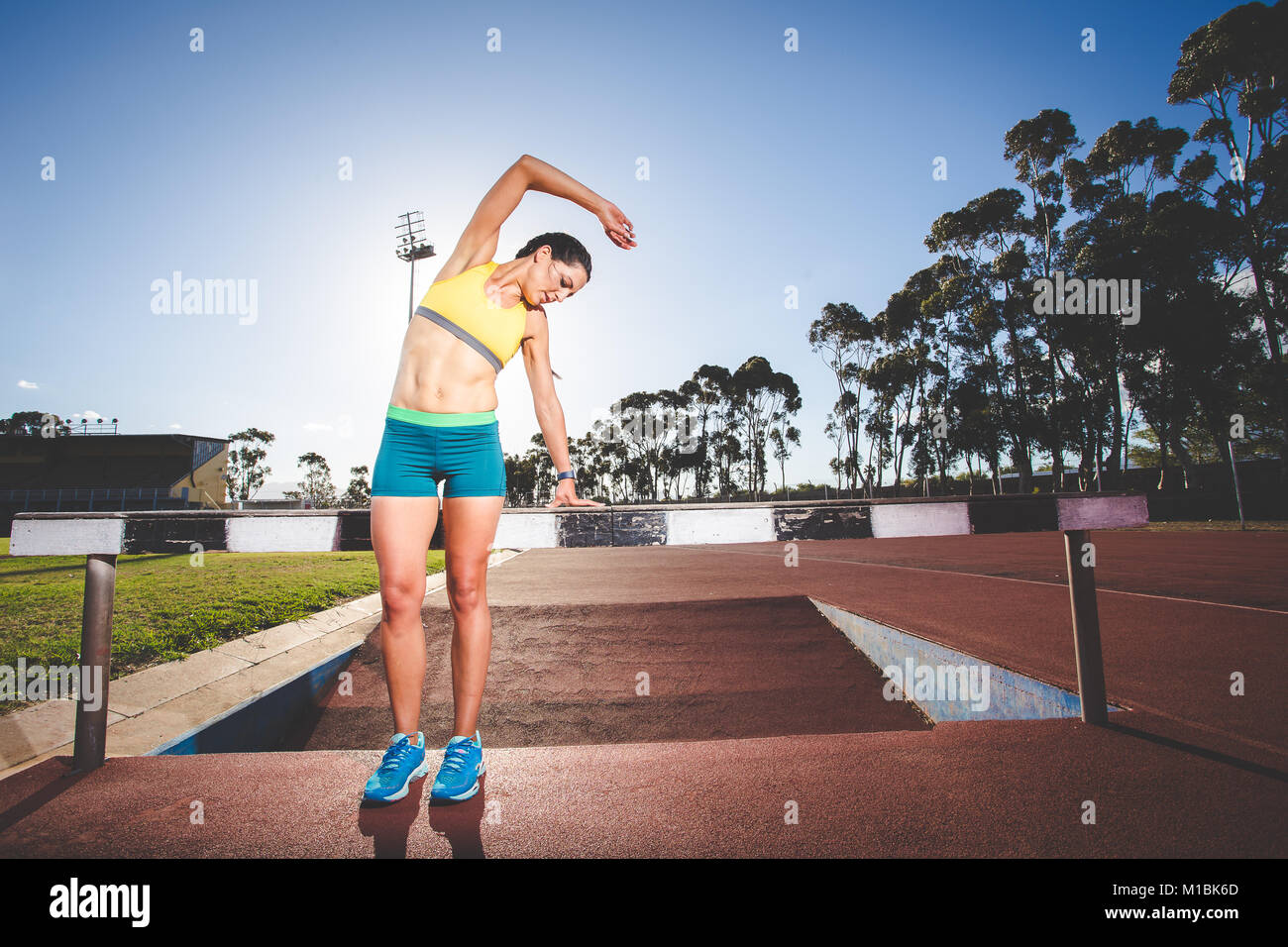 Female fitness model and track athlete sprinting on an athletics track ...