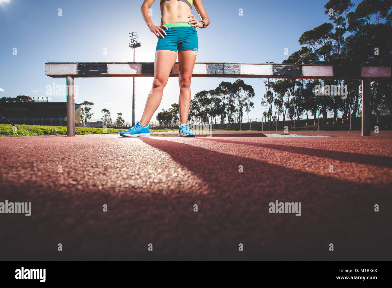 Female fitness model and track athlete sprinting on an athletics track ...
